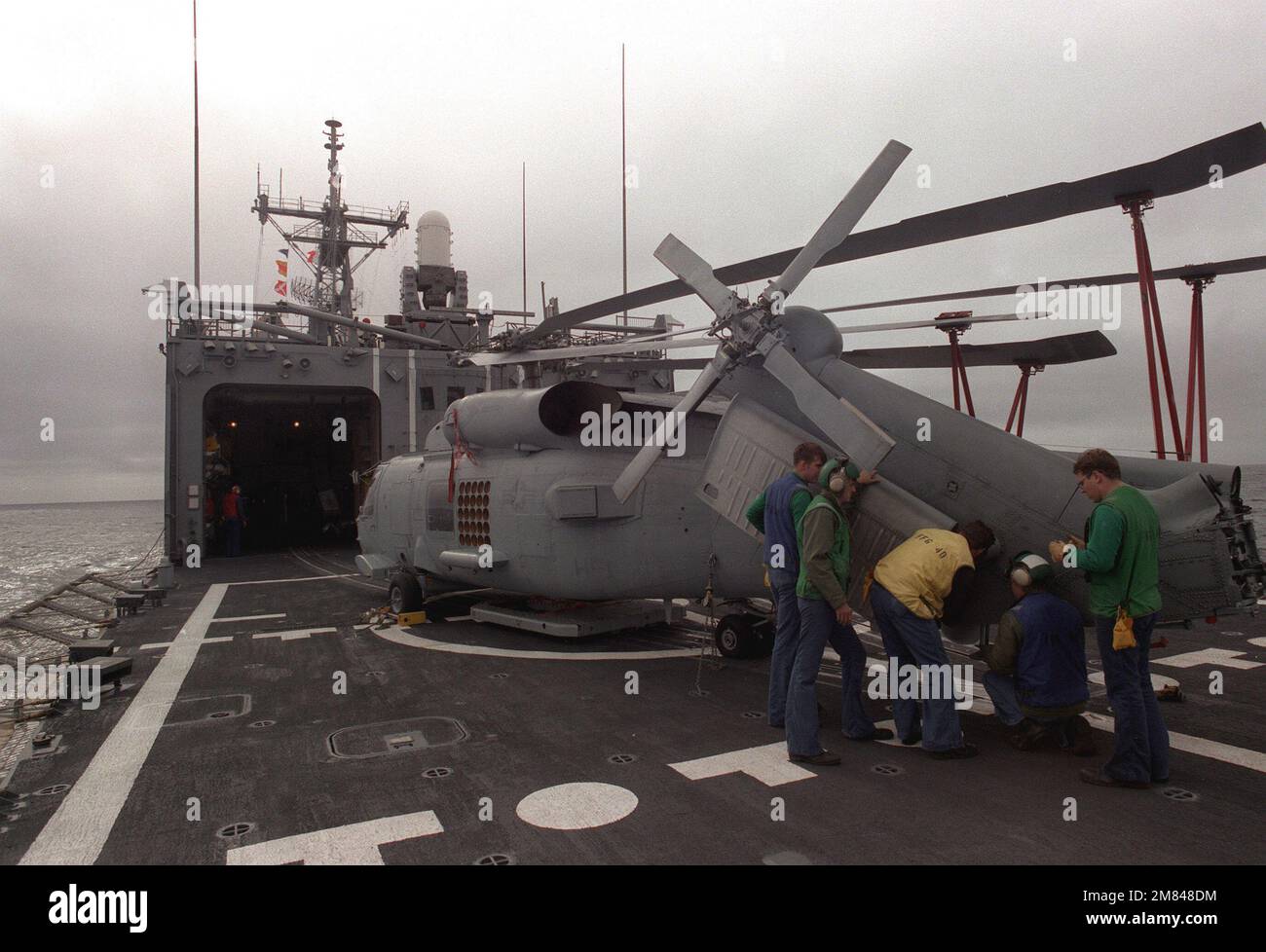Crew members lock the tail section of an SH-60B Sea Hawk in a folded ...
