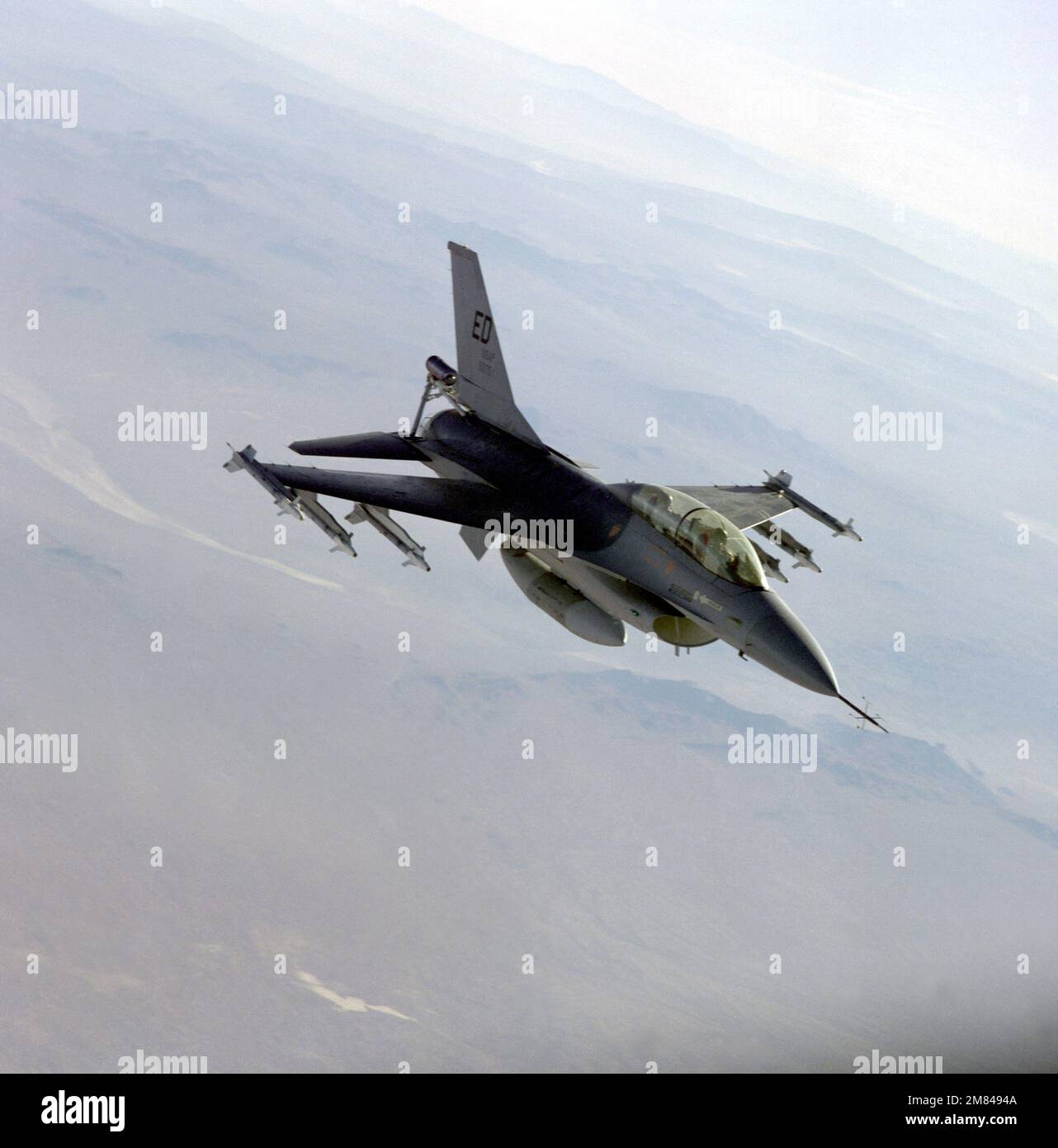 An air to air left side view of an F-16 Fighting Falcon aircraft armed ...