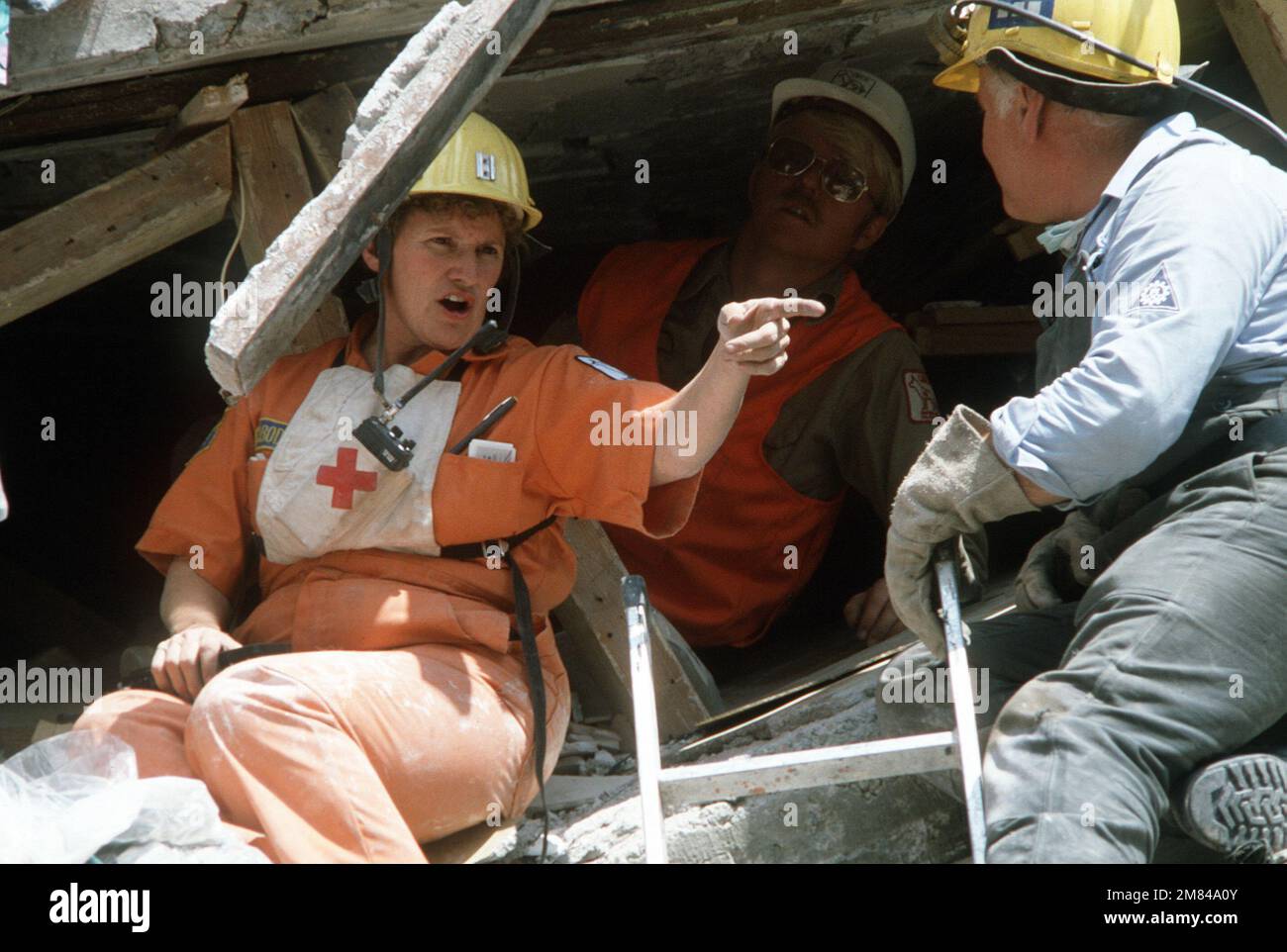 A search and rescue team member asks for quiet outside a collapsed ...