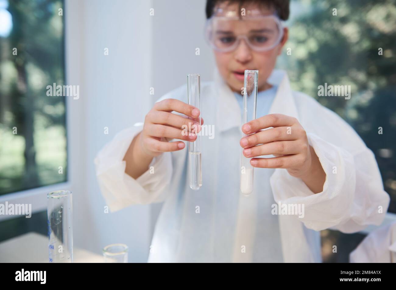 Focus on test tubes with chemicals and reagents in schoolboy's hands ...