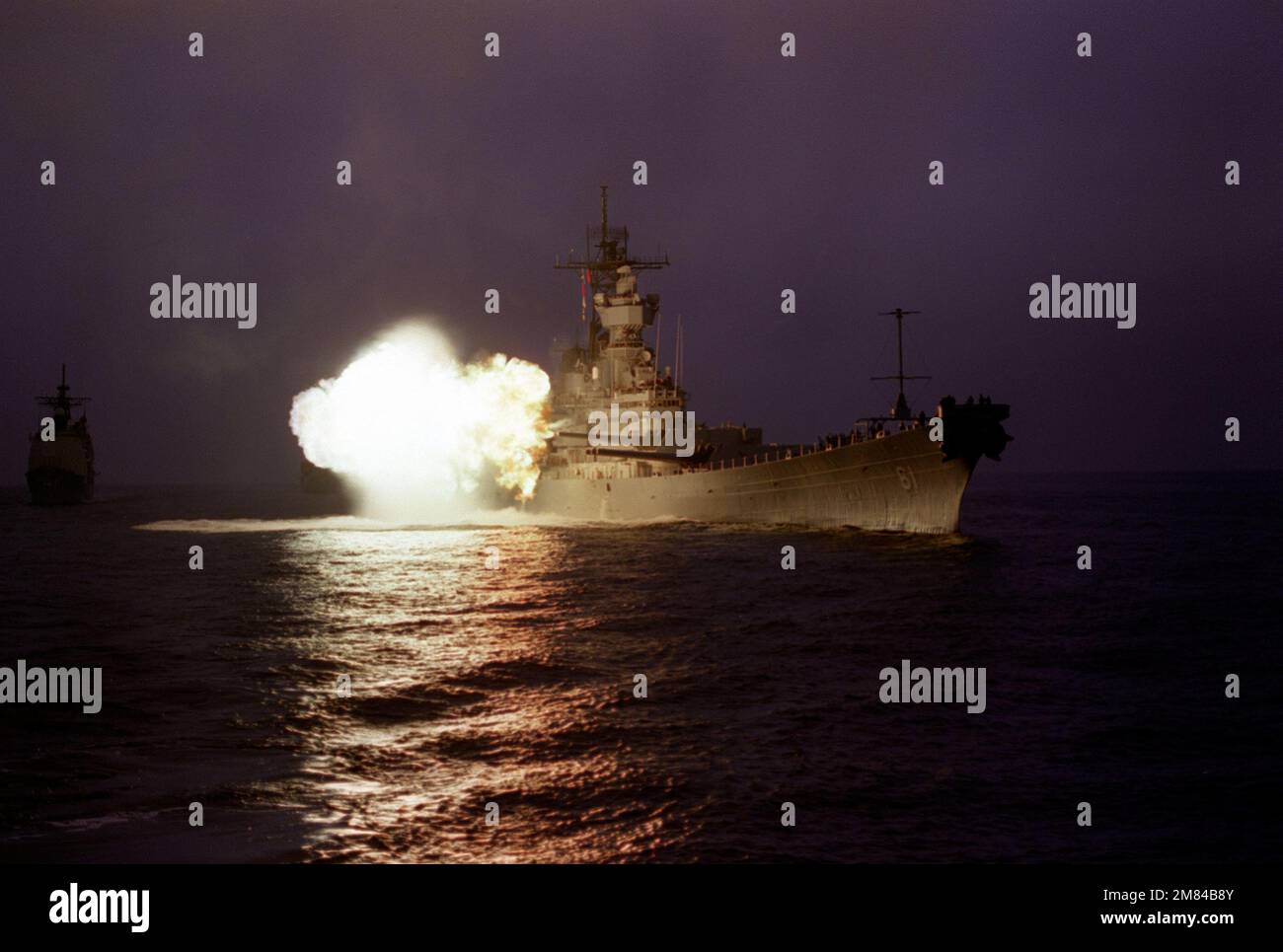 A starboard bow view of the battleship USS IOWA (BB-61) firing a ...