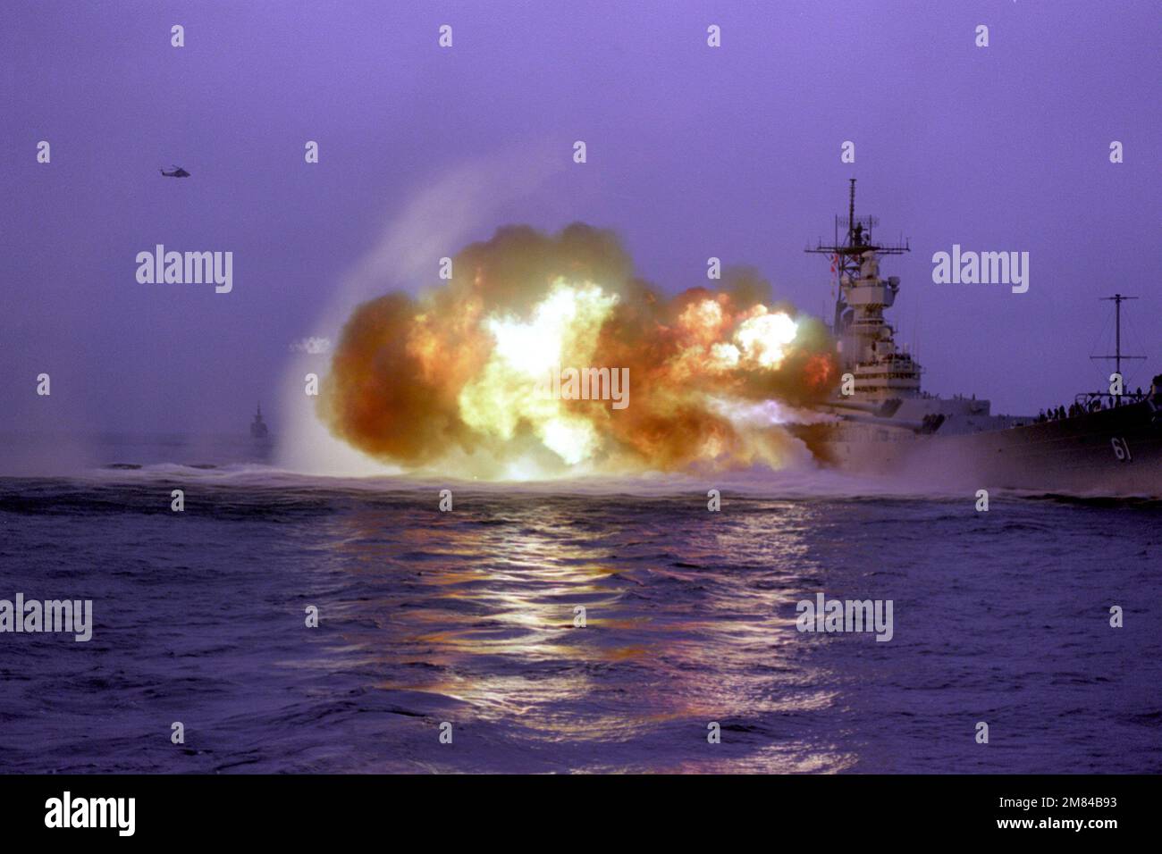 A starboard bow view of the battleship USS IOWA (BB-61) firing a ...