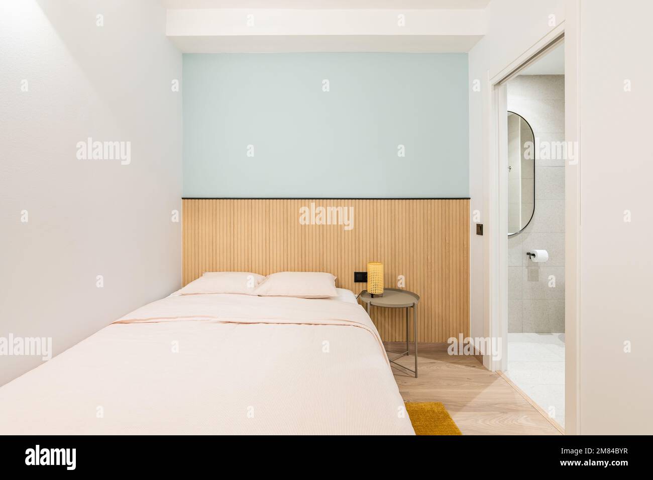Double bed against a shallow niche with a blue wall and wooden decor ...