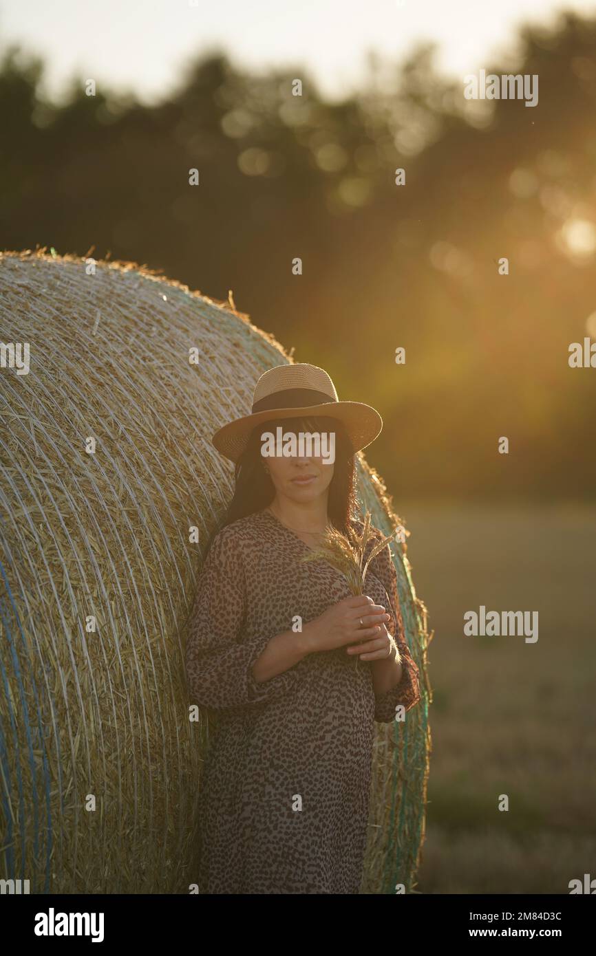Pretty woman model stands against a haystack in a straw hat Stock Photo ...