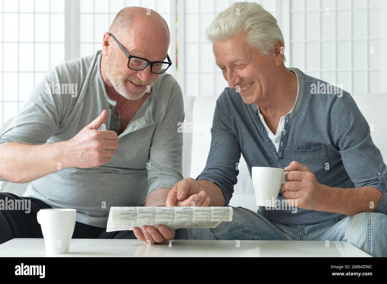 Two old men sitting at table and discussing news Stock Photo - Alamy