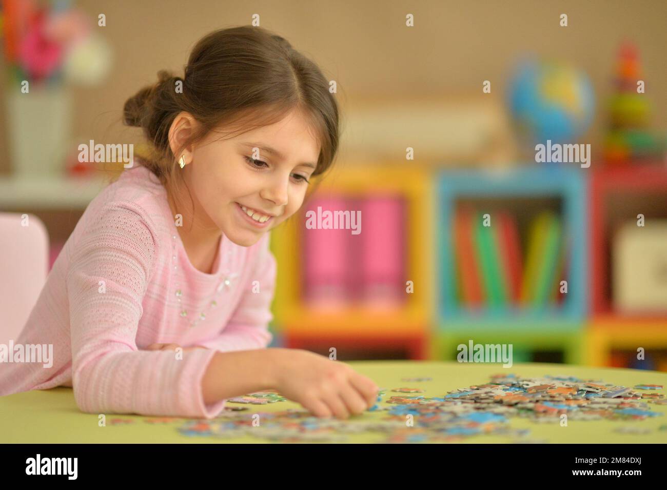 beautiful little girl collecting puzzle pieces at home Stock Photo - Alamy