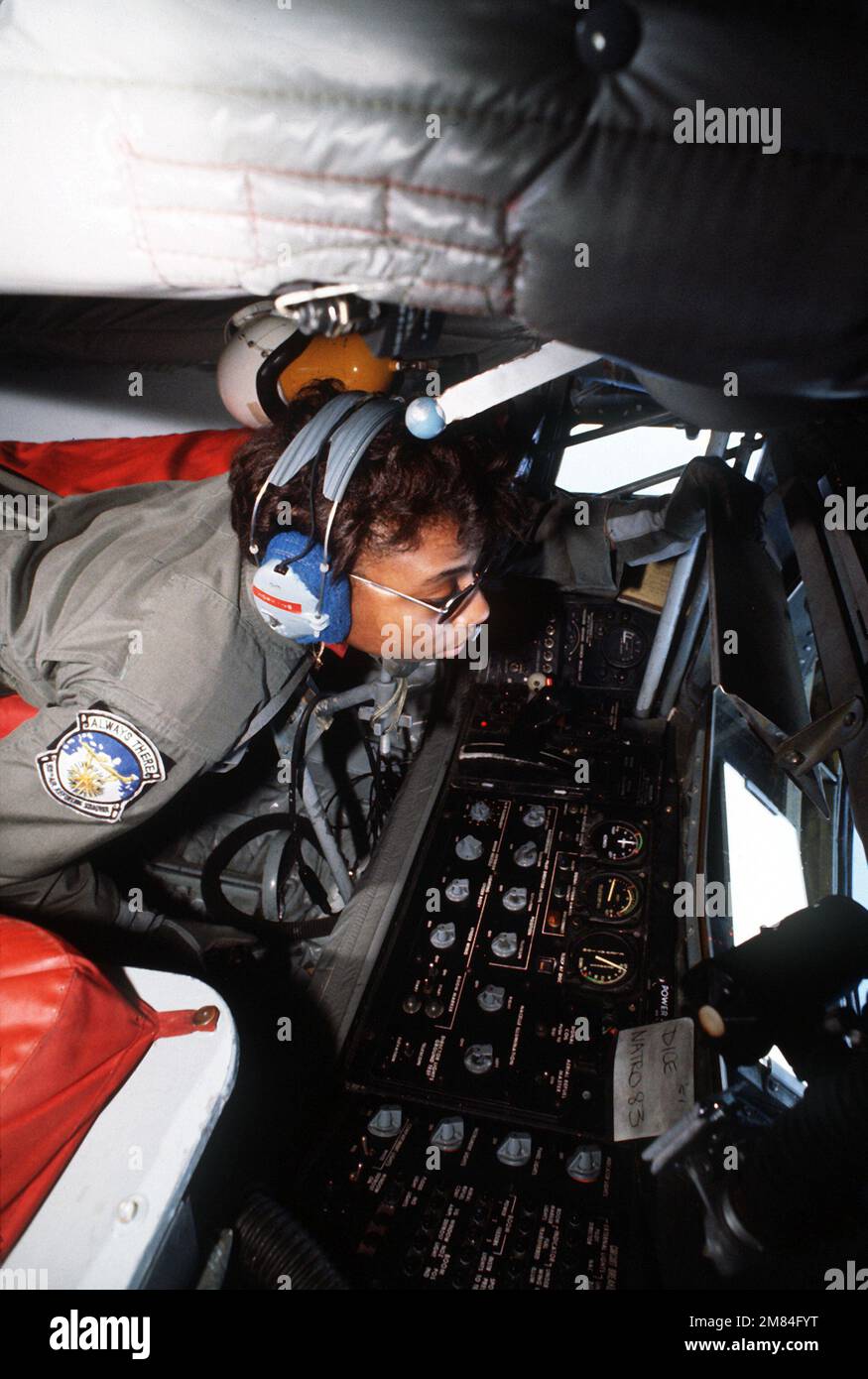 An aerial refueling boom operator looks out the observation window of a ...