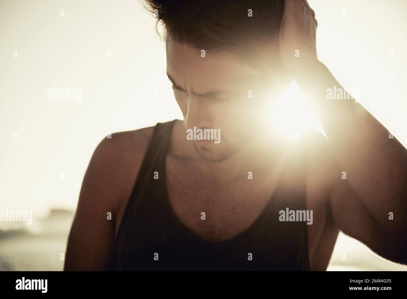 Basking in the sunlight. A handsome man standing on the beach at sunset ...