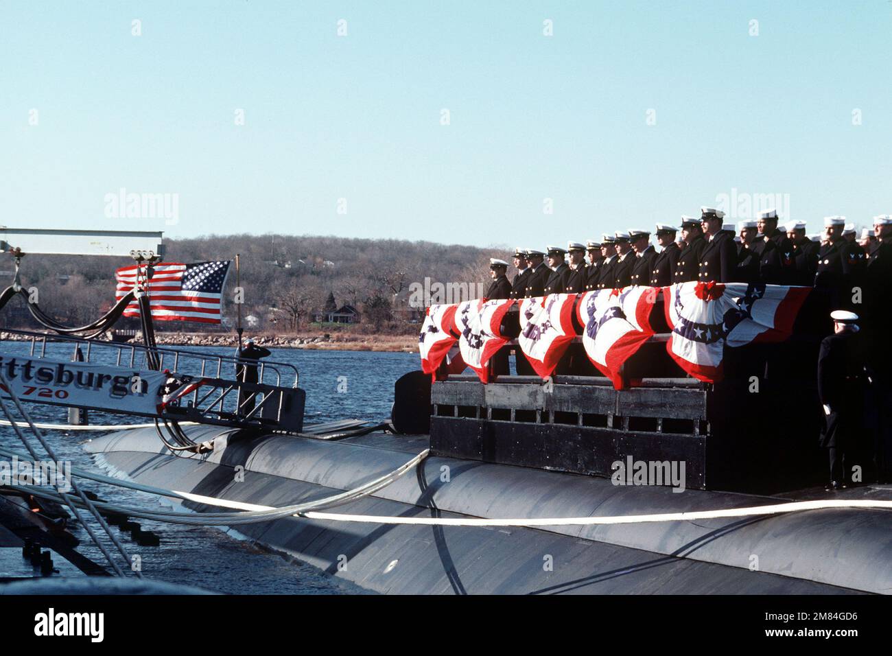 Crewmen stand at attention on a platform aboard the nuclear-powered ...