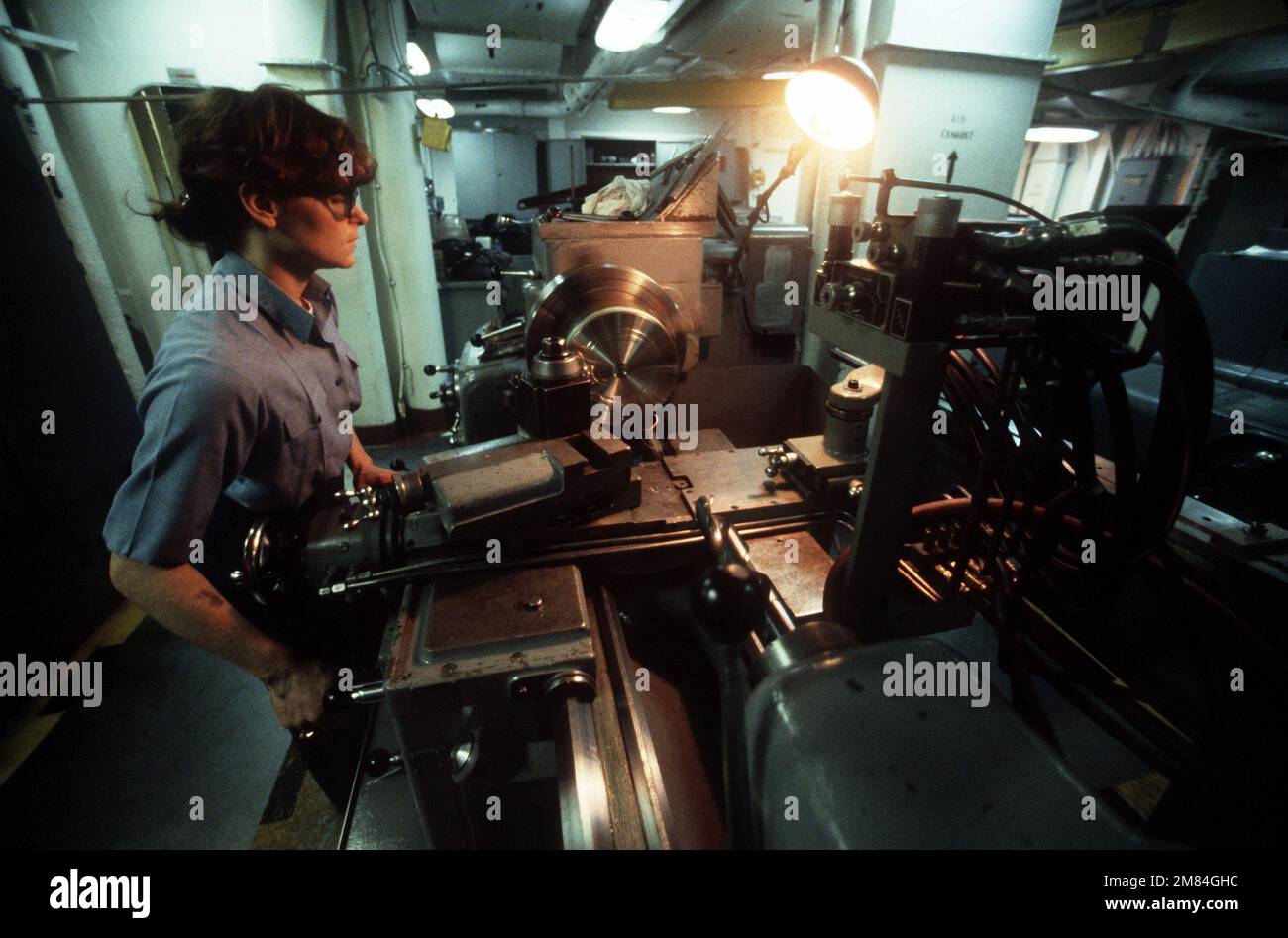 A female machinist operates a metal lathe at Navy Fleet Ballistic ...