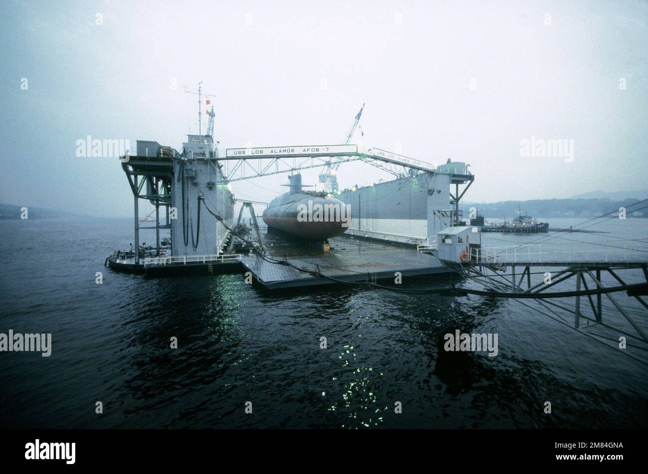 A submarine rests inside the large auxiliary floating dry dock USS LOS ...