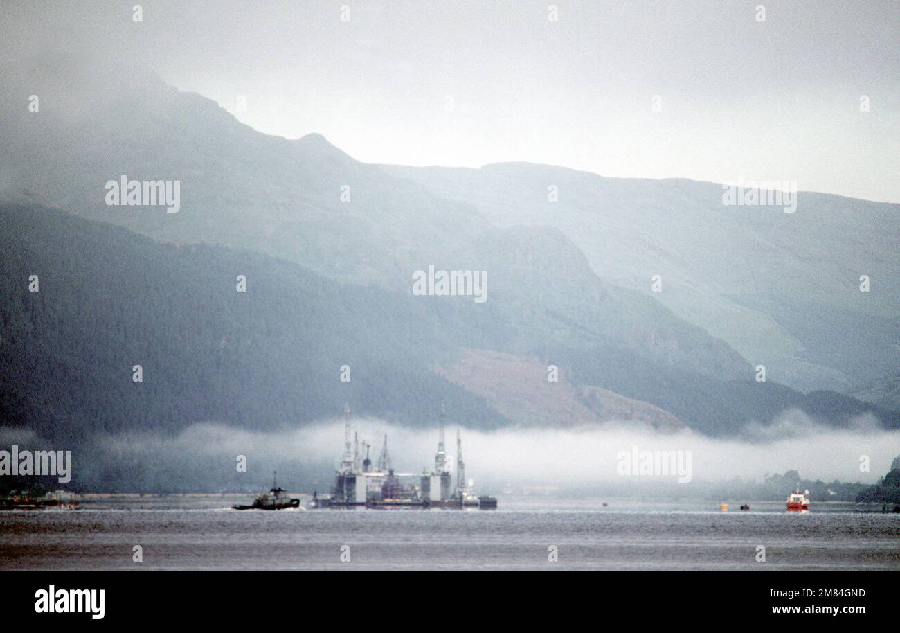 A tug approaches the large auxiliary floating dry dock USS Los Alamos ...