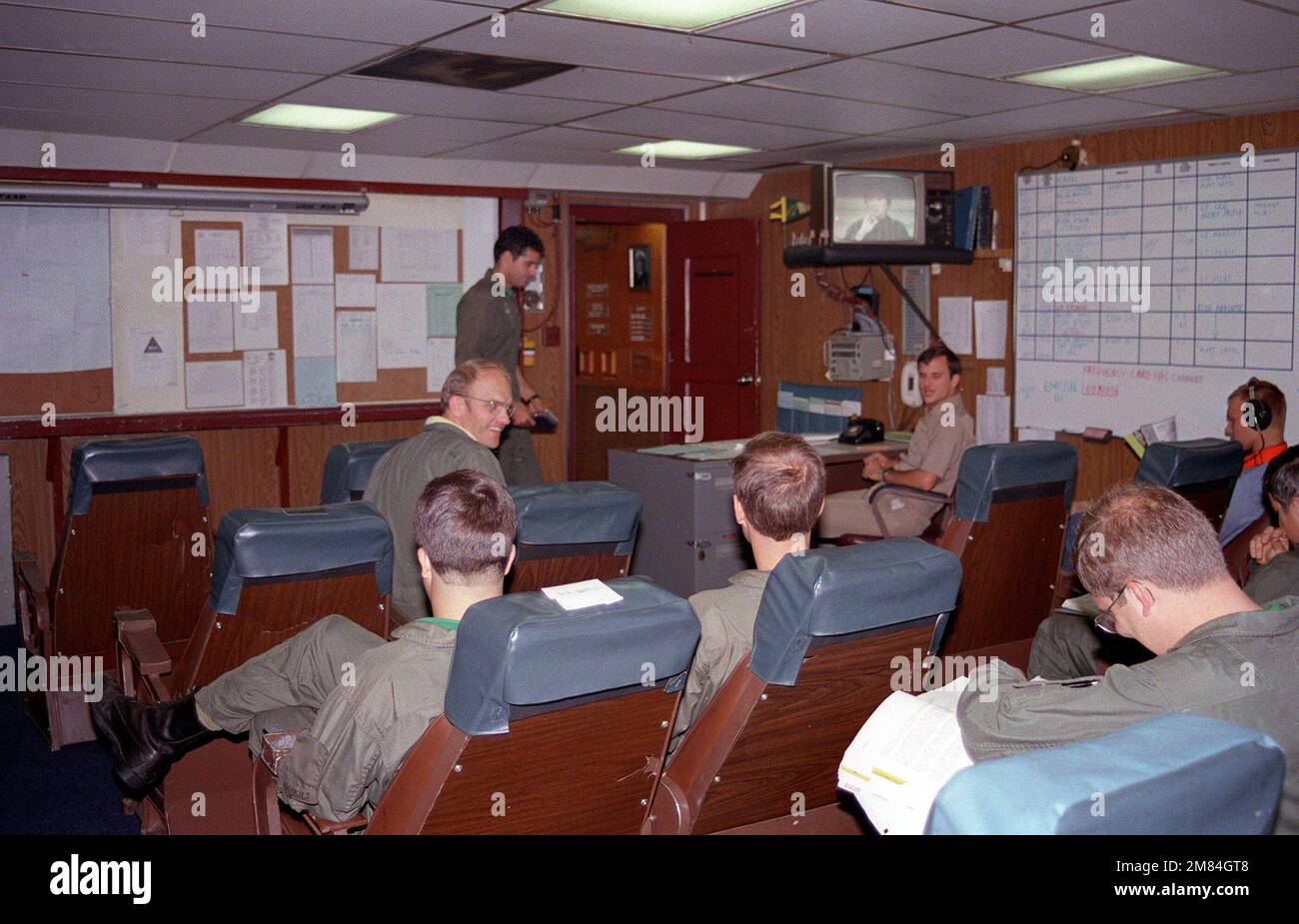 Pilots discuss flight operations in a briefing room aboard the aircraft ...