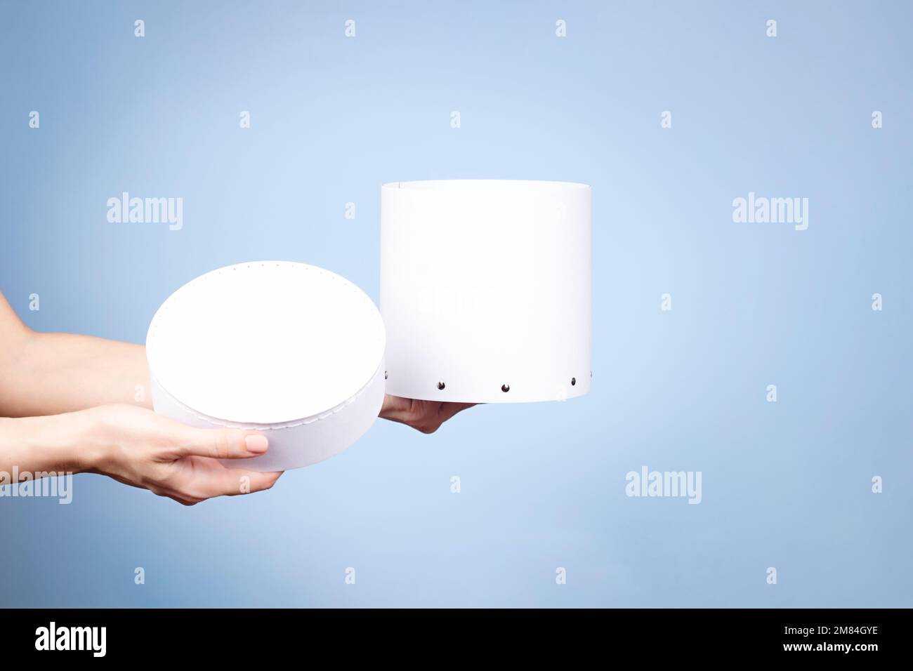 Woman hands holding white round cardboard box and open cap on light ...