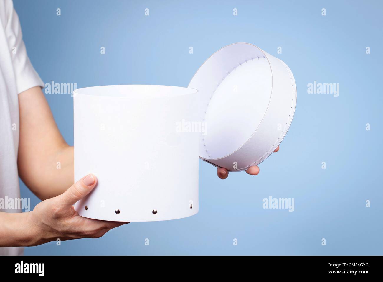 Woman hands holding white round cardboard box and open cap on light ...