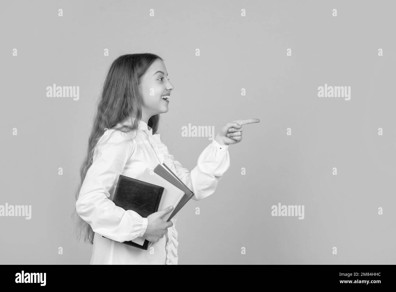 happy child with school book pointing finger on yellow background with ...