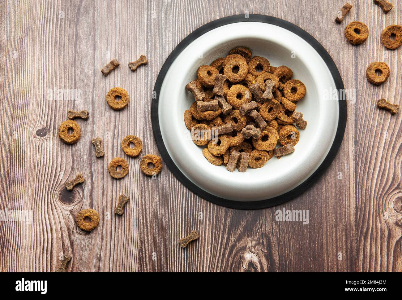 A bowl of dog food on a wooden floor. Dry feed pellets of various ...