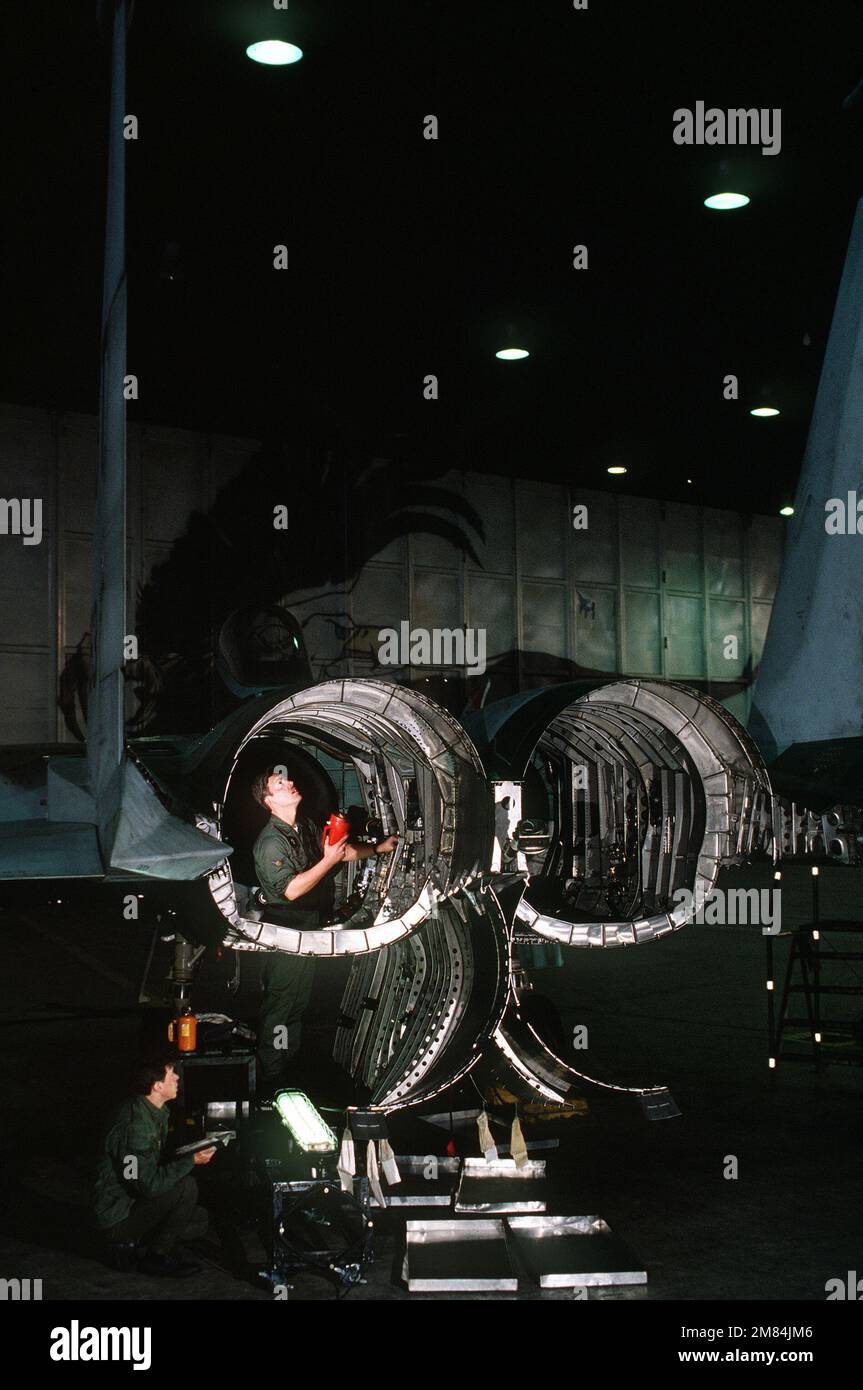 A USAF maintenance man stands inside the engine port of an F-15 Eagle ...