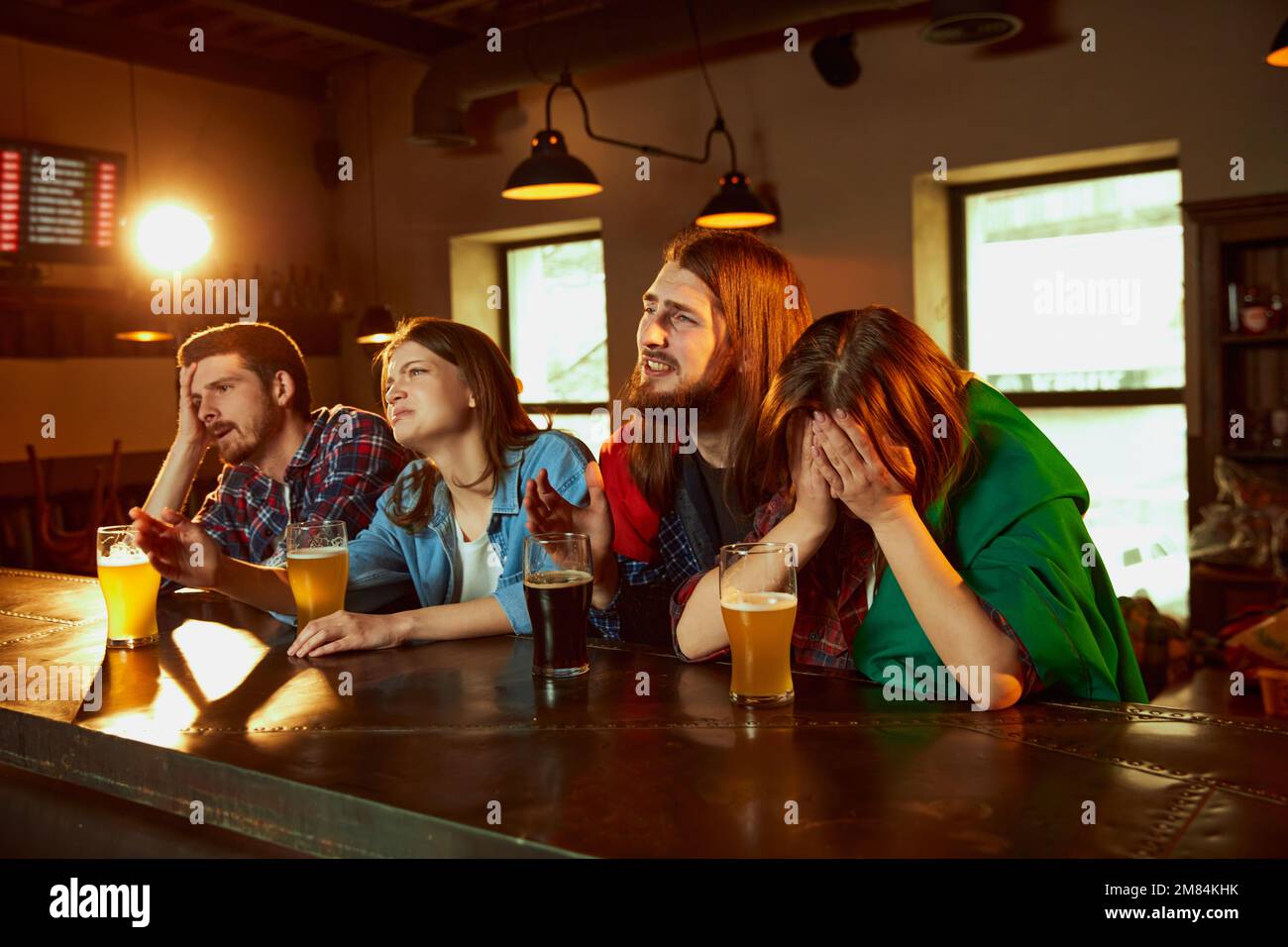 Friends, sport fans meeting at the pub to watch match and drink beer ...