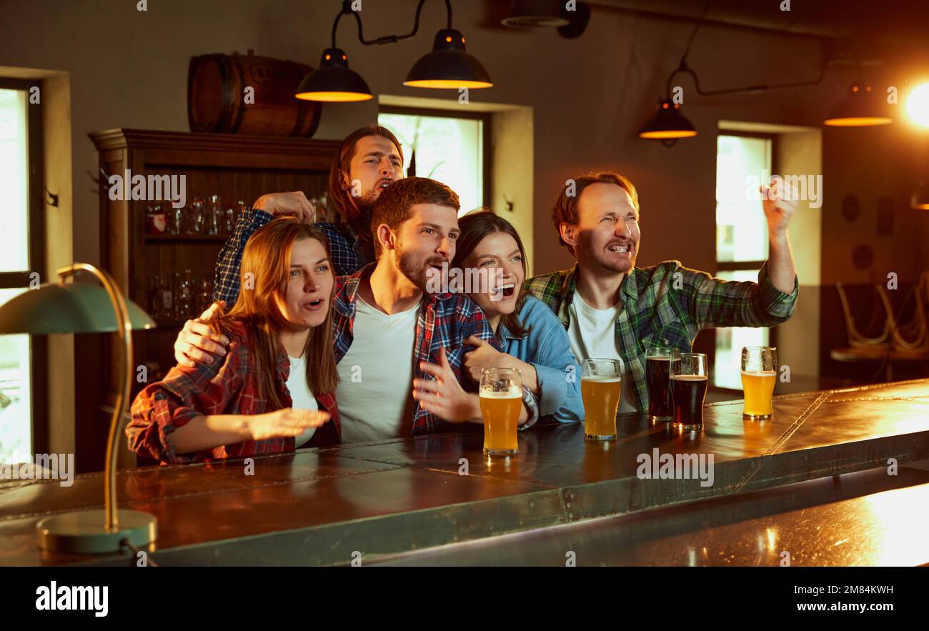Friends, young people, men and women watching match at pub. Fans ...