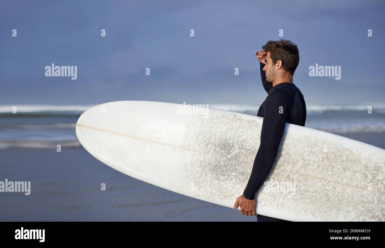 Ready to take on the waves. a young man about to go surfing Stock Photo ...