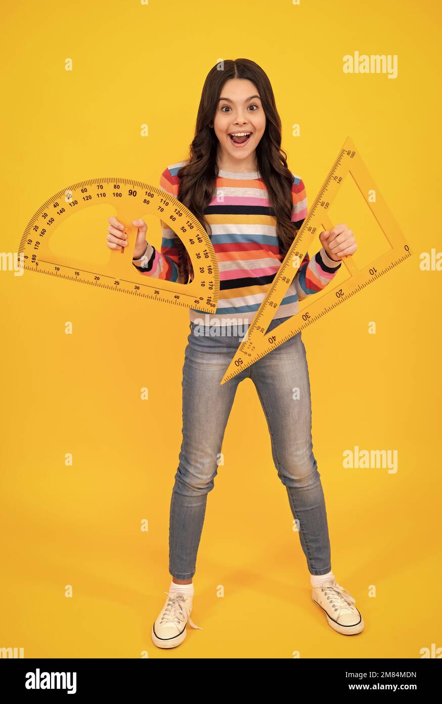Back to school. School girl hold ruler measuring isolated on yellow ...