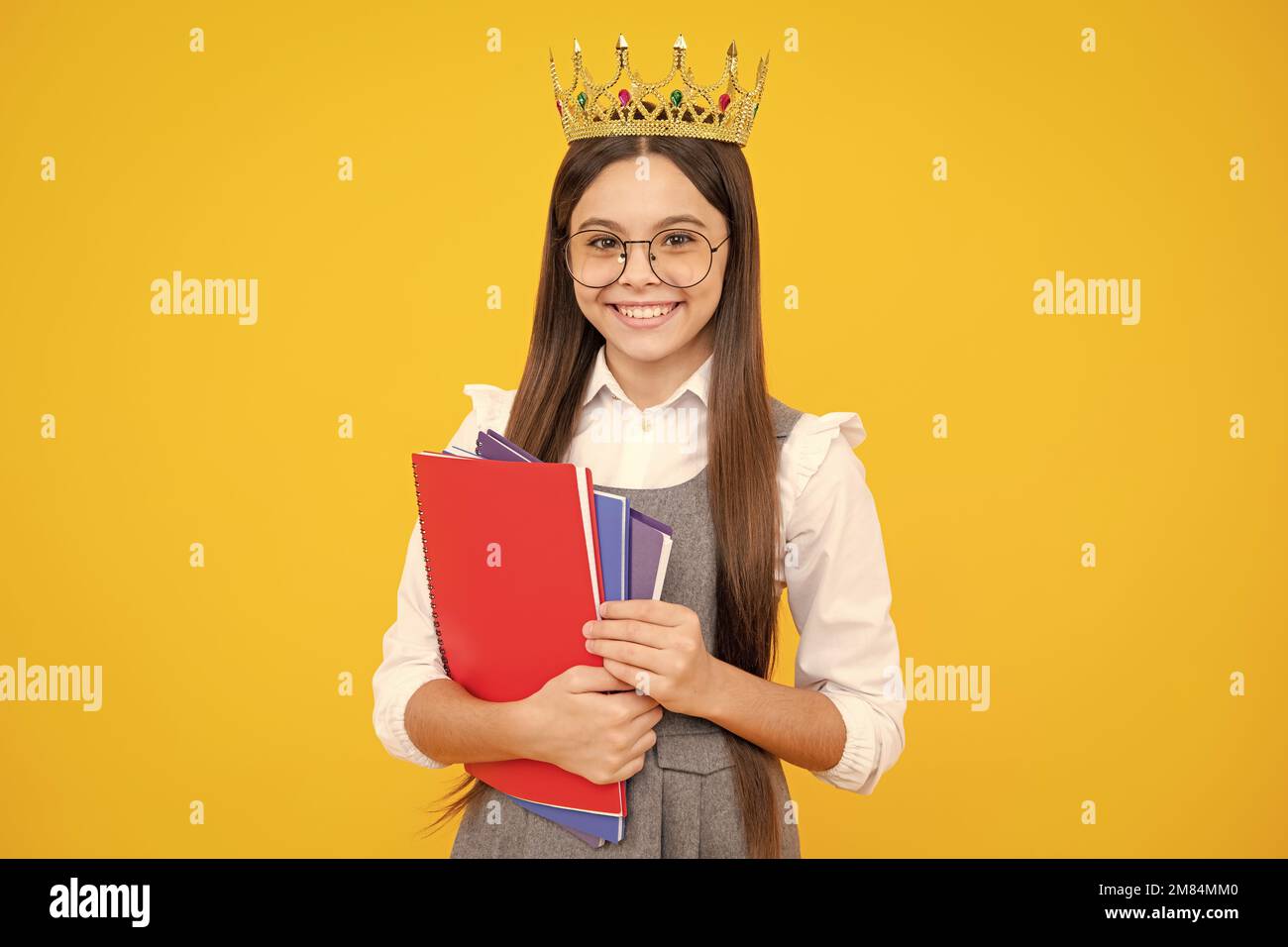 Schoolgirl in school uniform and crown celebrating victory on yellow ...