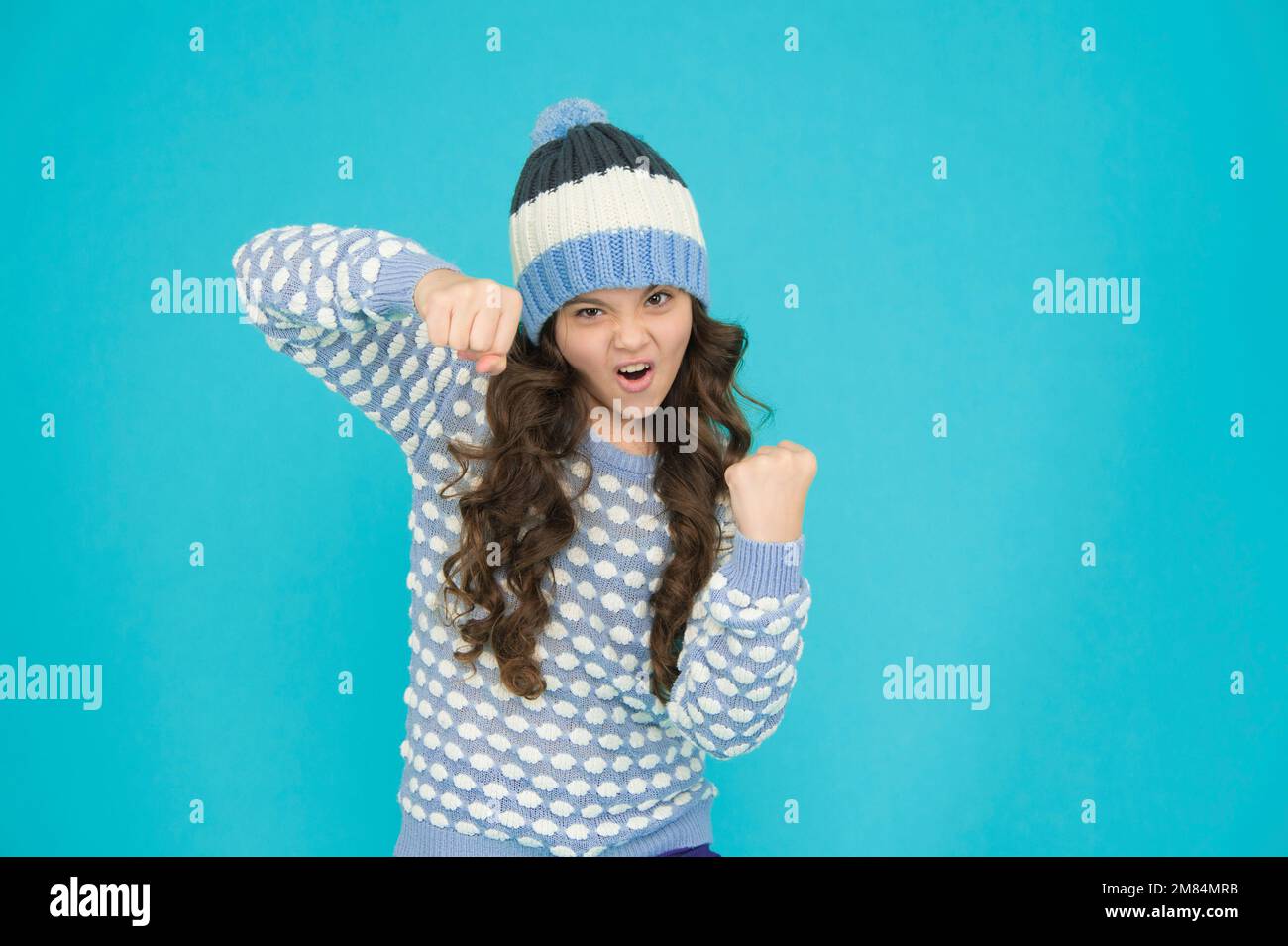 angry kid girl punching and warming up in winter knitted hat and ...