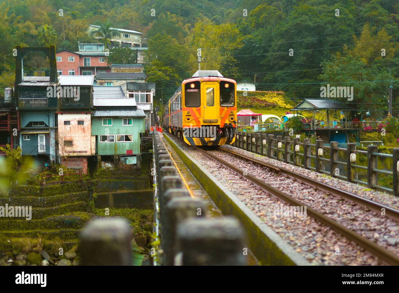 The yellow train is passing through a small village in the valley ...