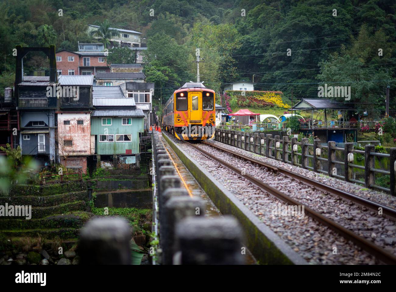 The yellow train is passing through a small village in the valley ...