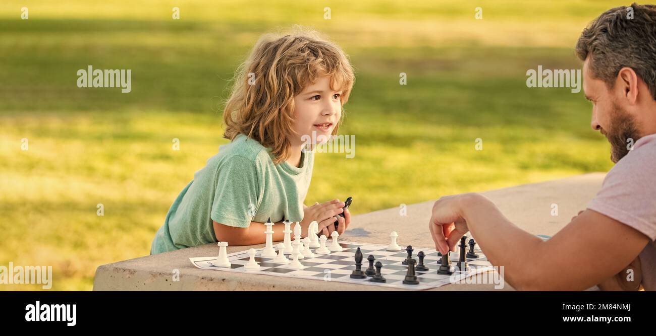Father and son play chess outdoor, banner poster with copy space, happy ...
