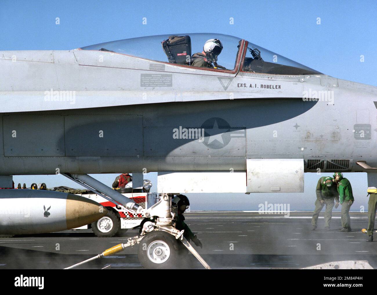A flight deck crewman checks the catapult attachments of an F/A-18A ...