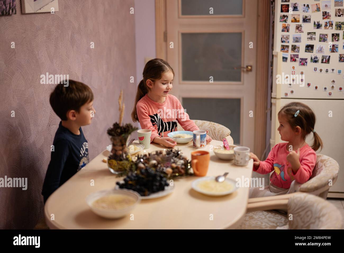 Three kids have dinner together in the kitchen Stock Photo - Alamy