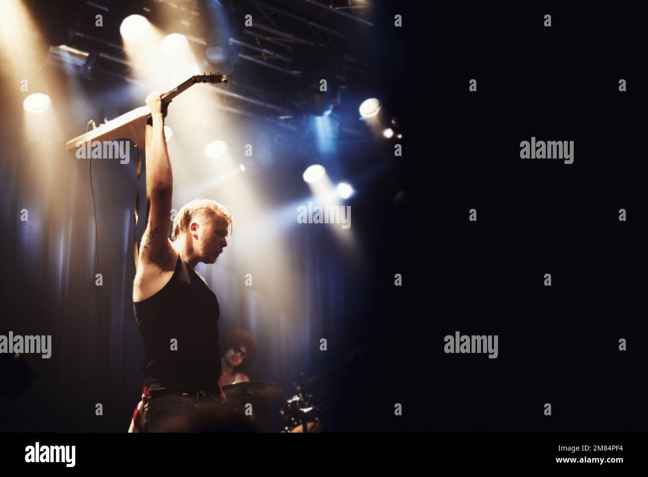 Rocking out. A guitarist on stage with his band beneath strobe lights ...