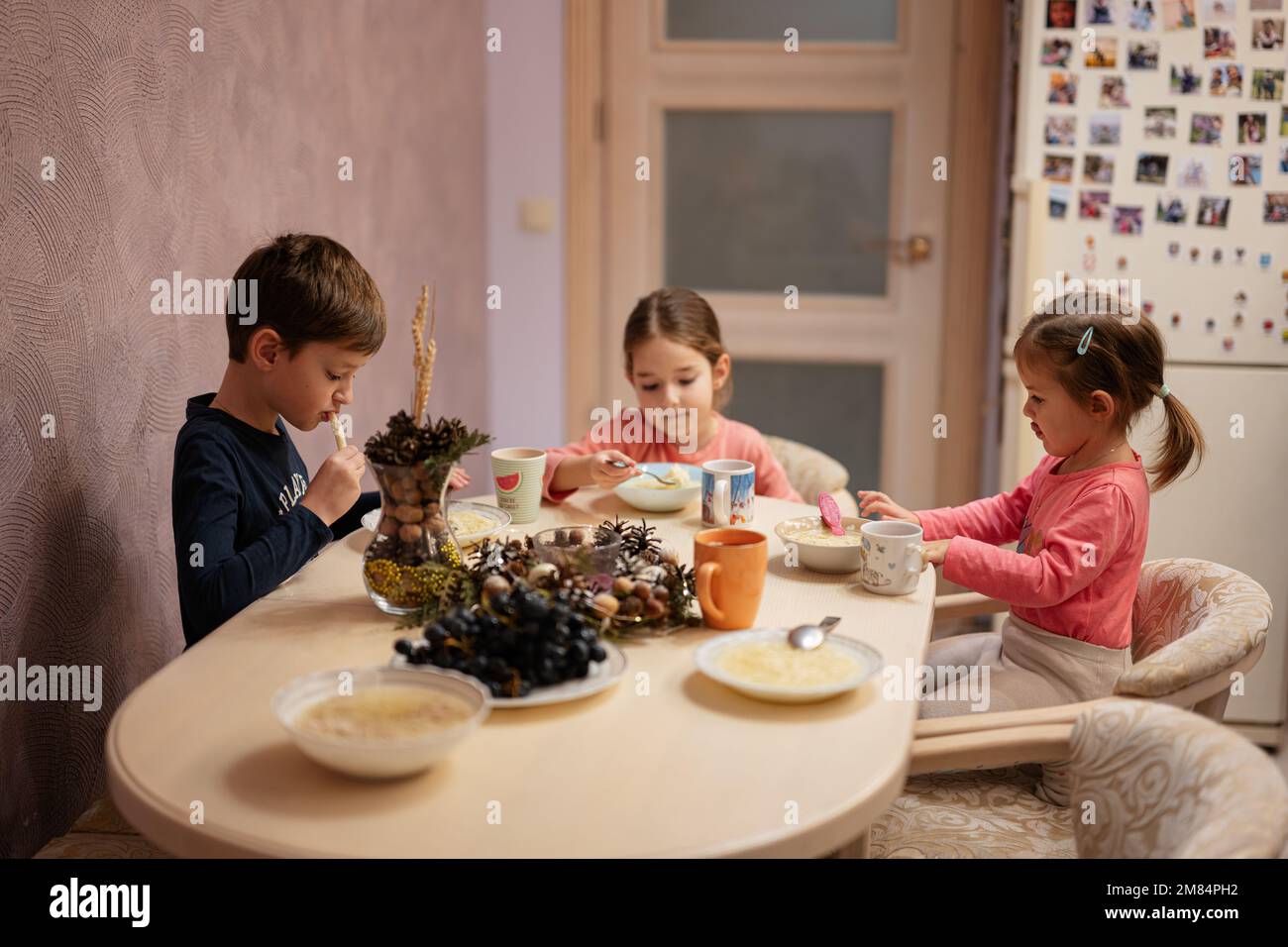Three kids have dinner together in the kitchen Stock Photo - Alamy