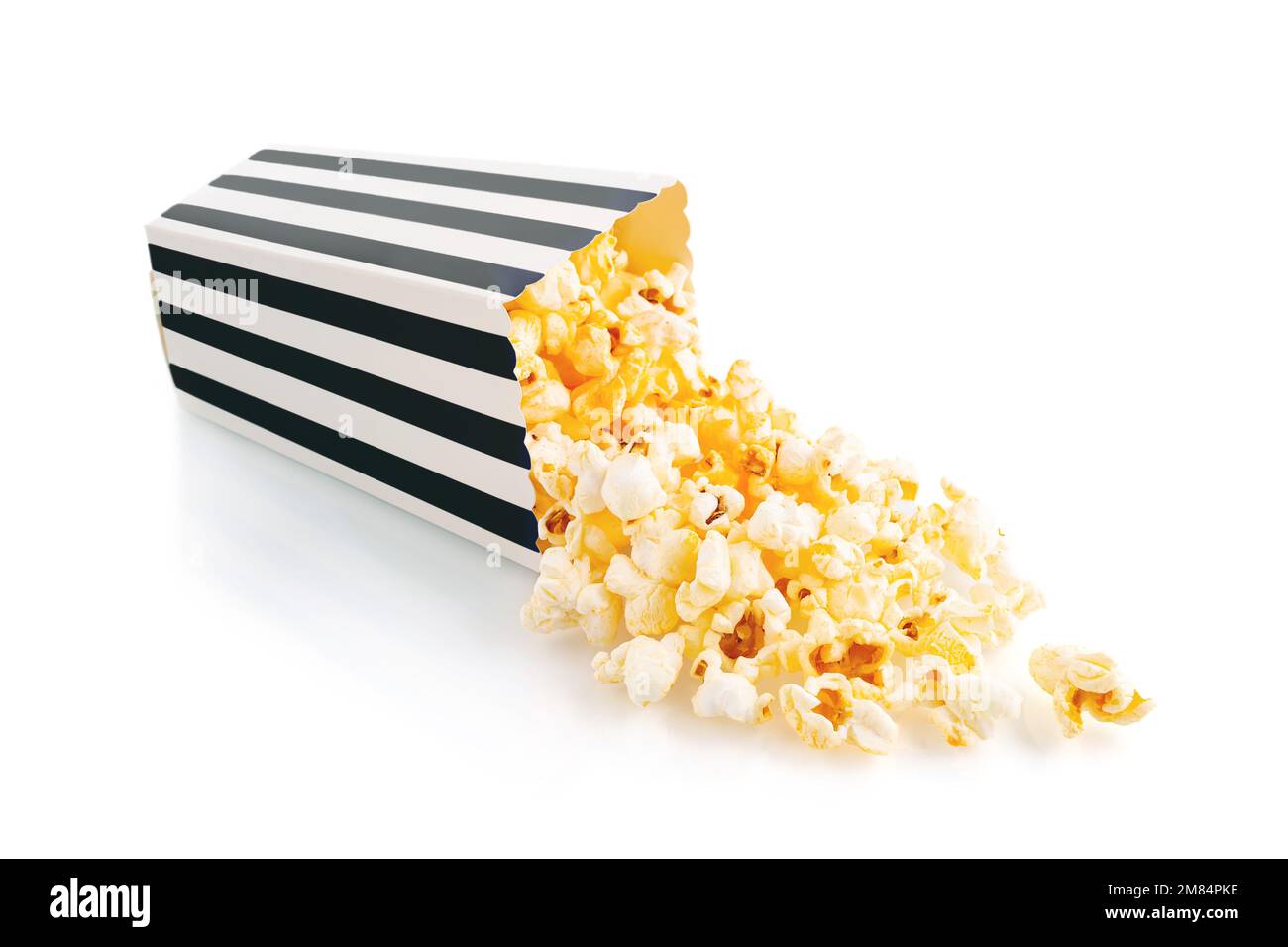 Tasty cheese popcorn falling out of a black striped carton bucket ...