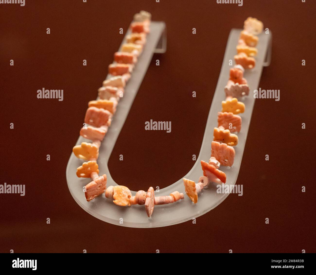 A necklace of bird heads carved from coral and red conch shell in the ...