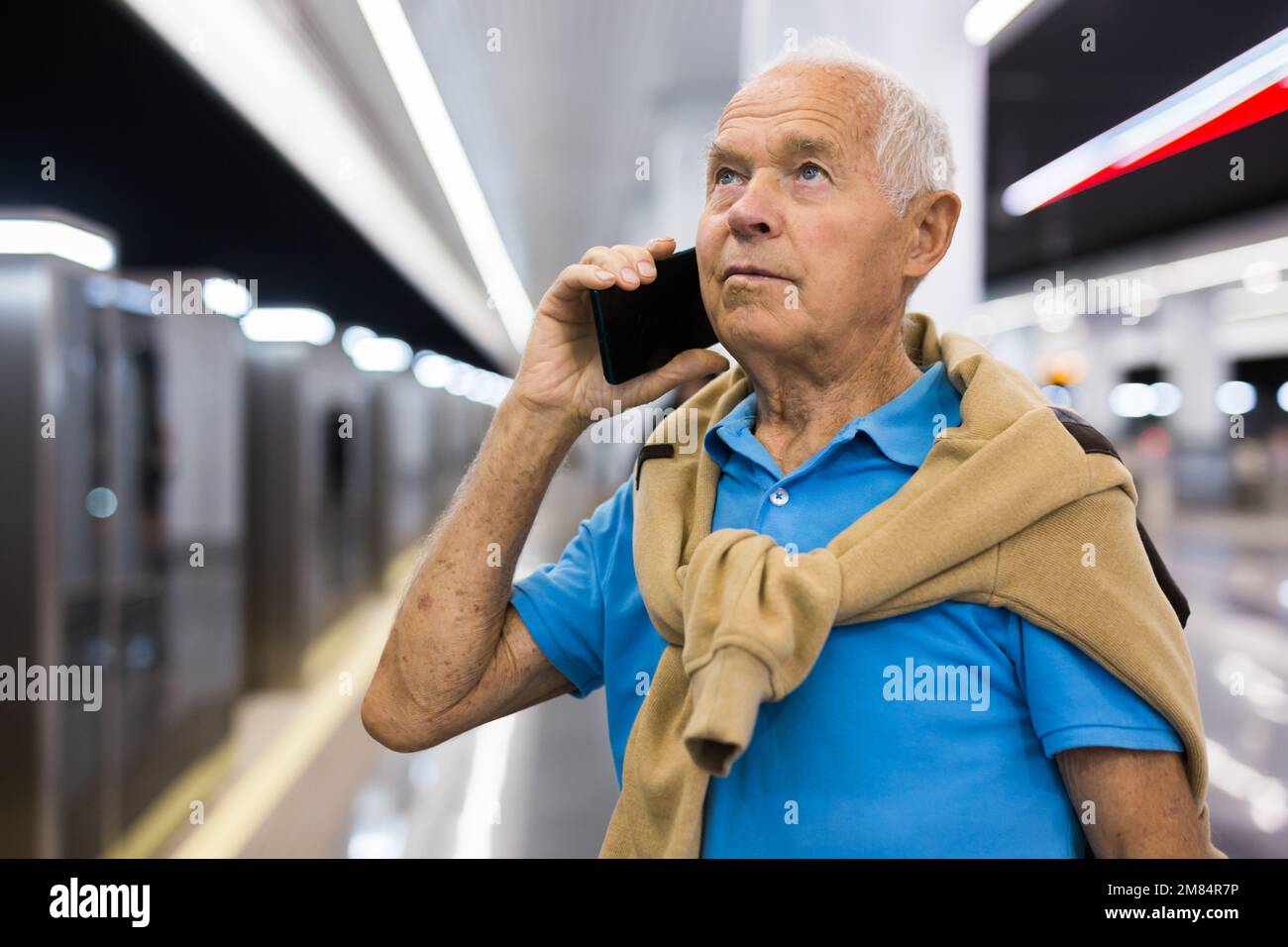 Portrait of man standing in underground station and talking on mobile ...