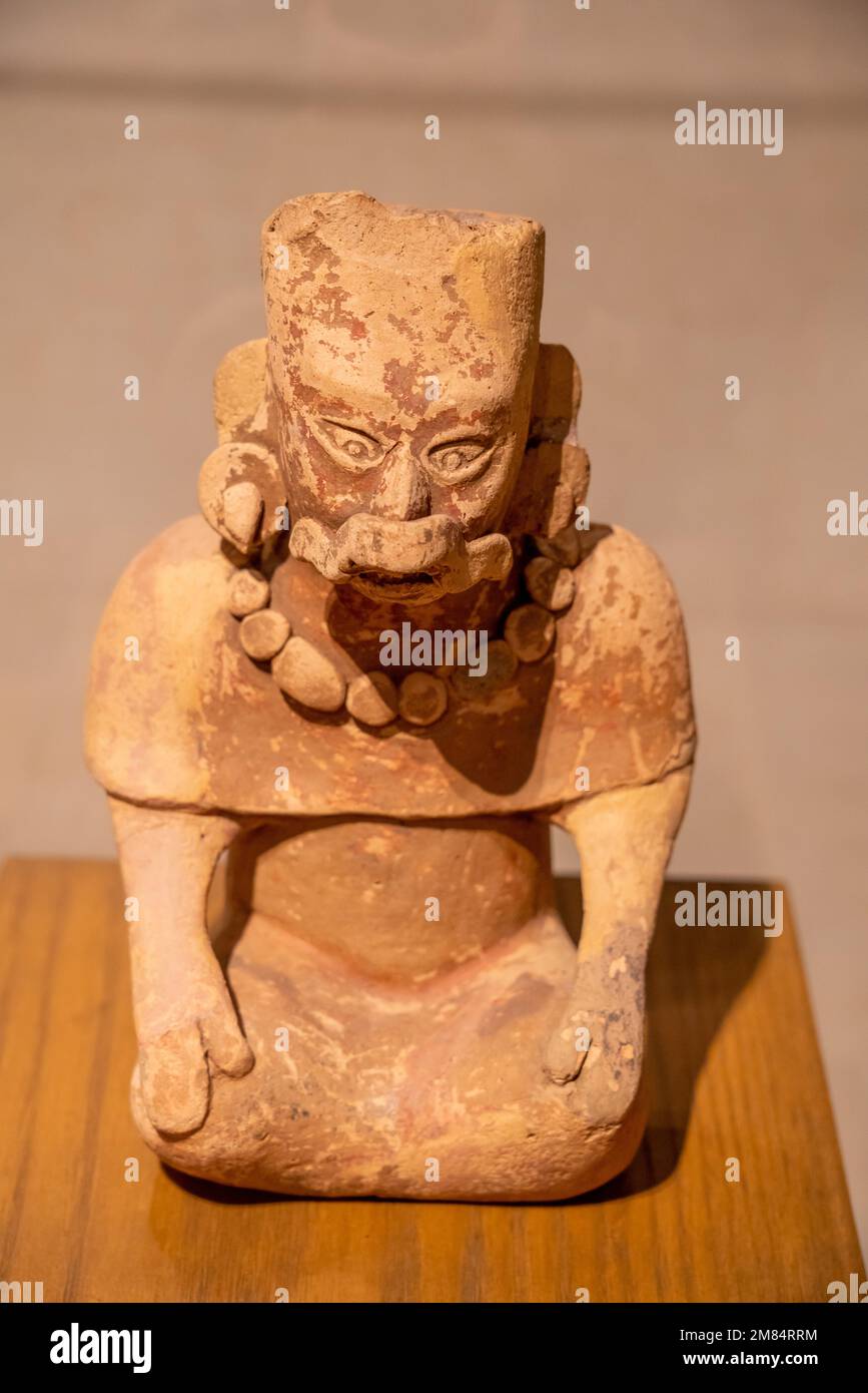 Pre-Hispanic Zapotec ceramic figure of a kneeling man with a mask over ...