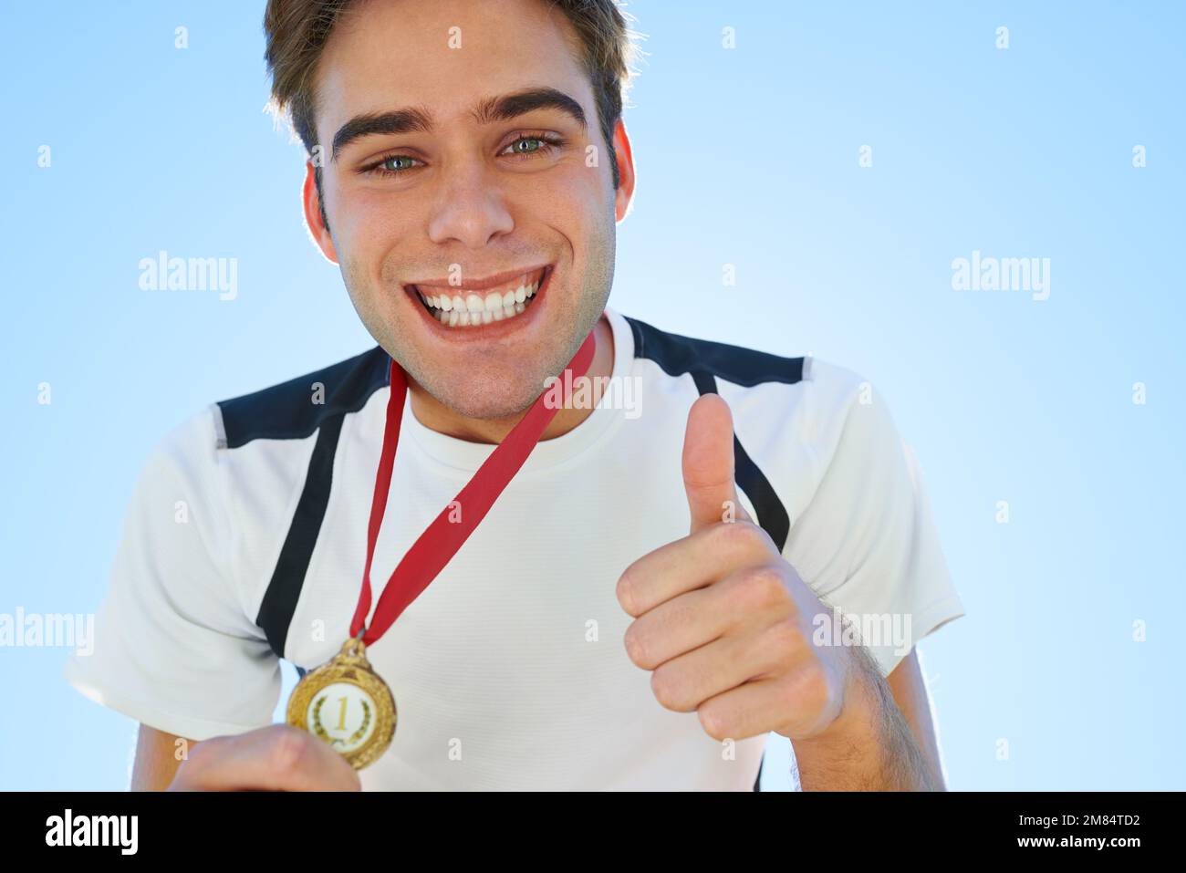 Proud sporting moment. Smiling medal winner gesturing thumbs up with a ...