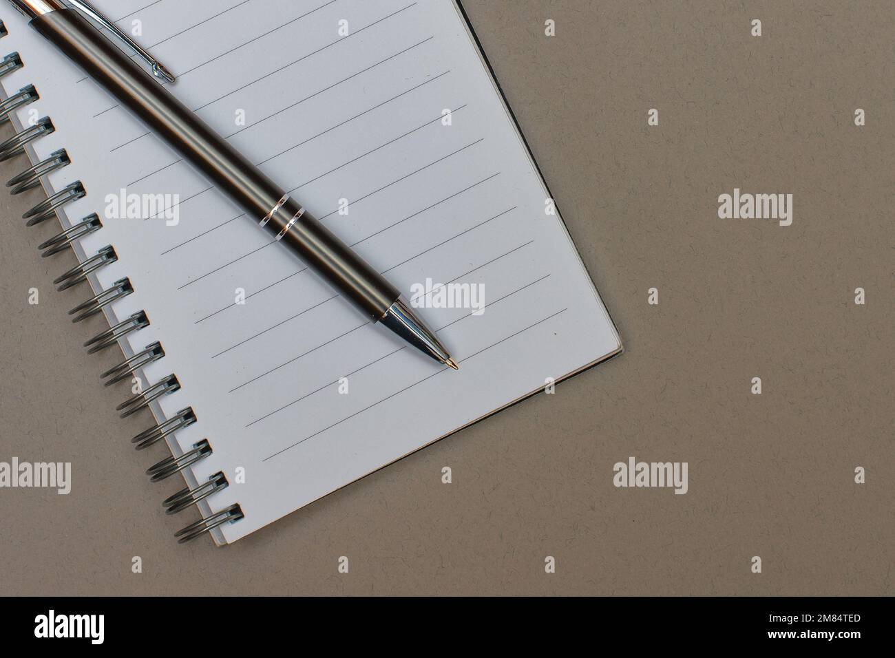 A Notebook With A Blank Page And A Pen Resting On It On Sand-colored ...