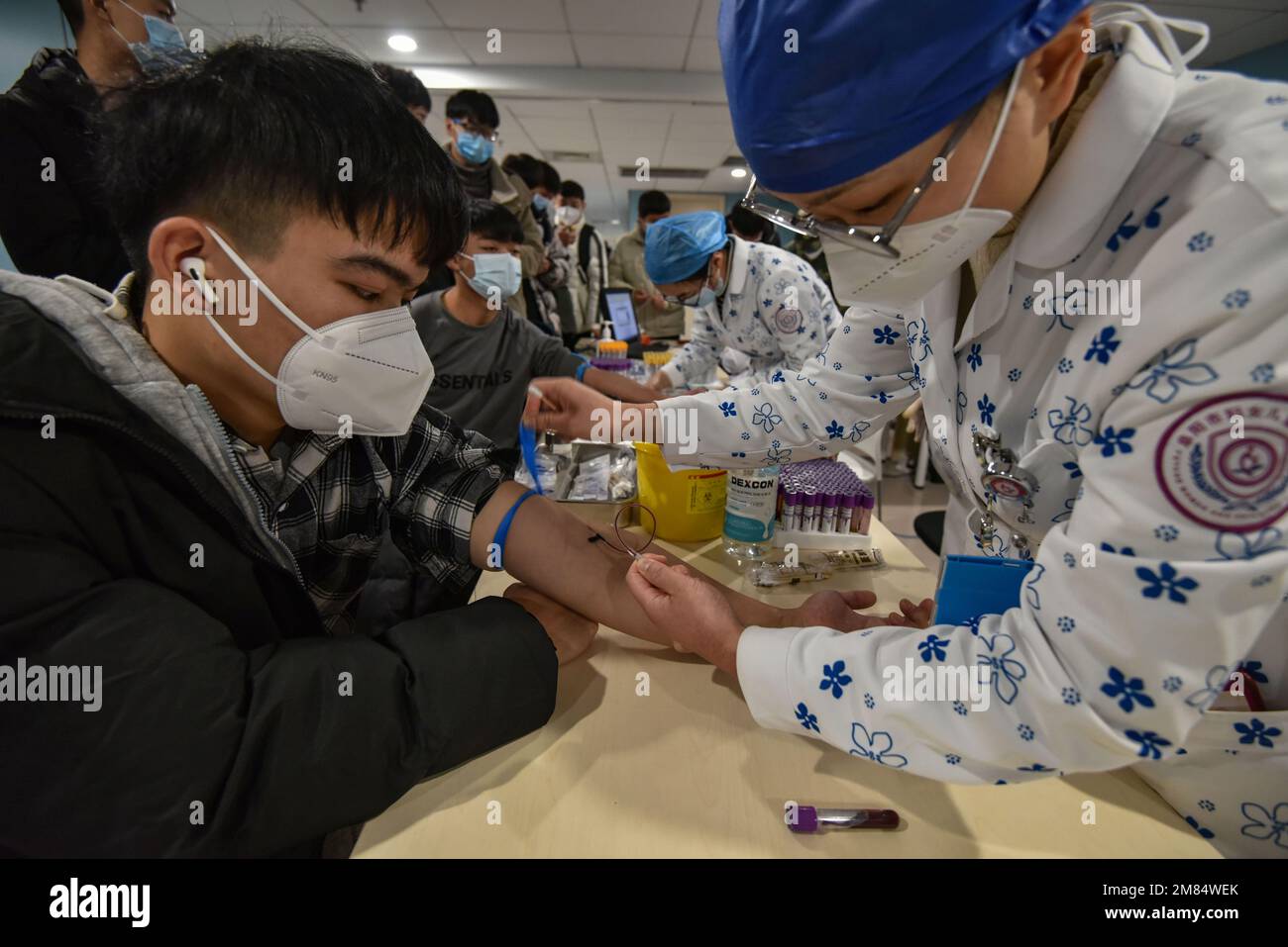 Fuyang, China. 12th Jan, 2023. A nurse draws blood from a young man for ...