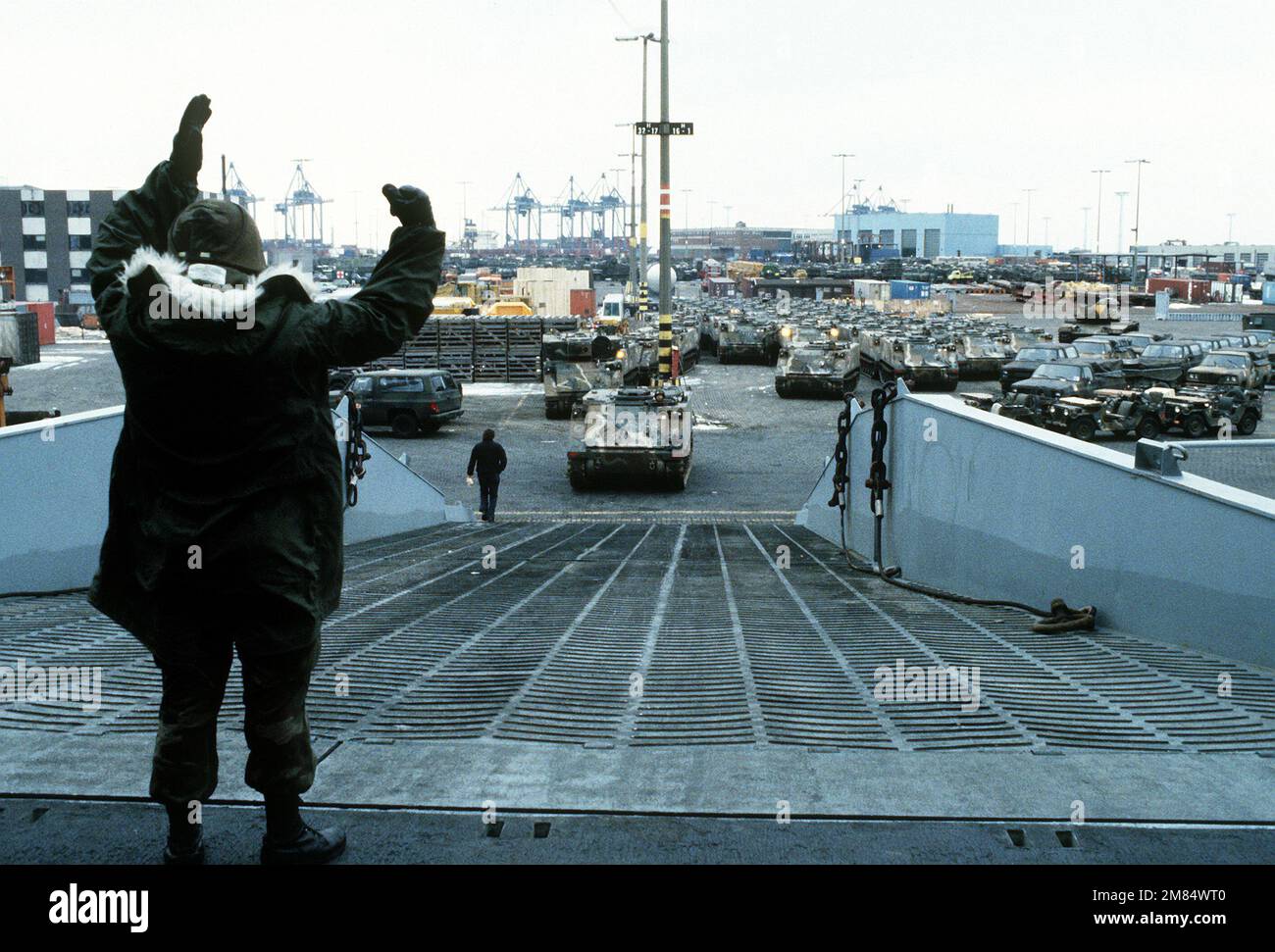 An M-113 armored personnel carrier is guided up the loading ramp of the ...