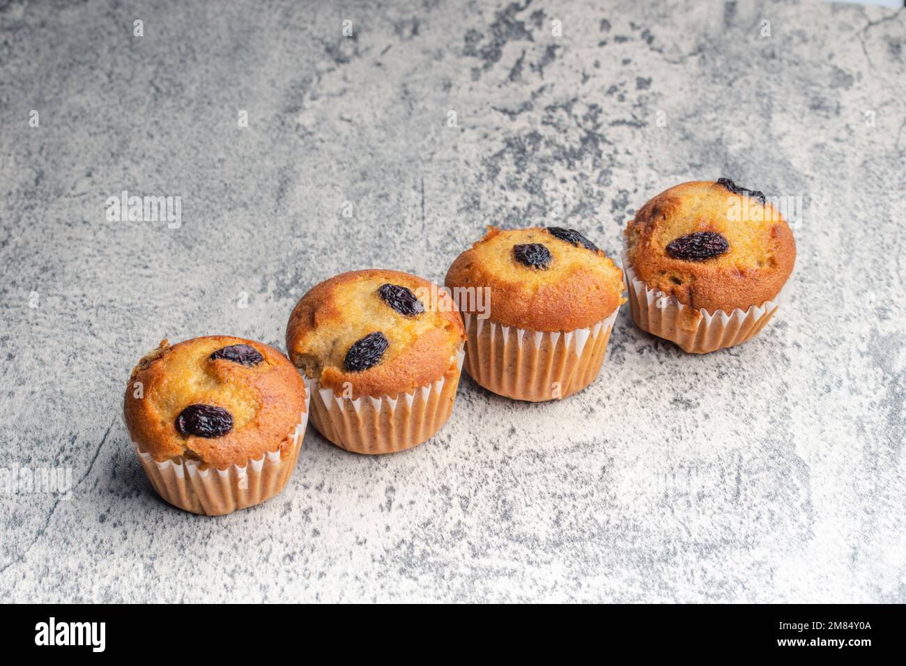 Banana cupcakes sprinkled with raisins. Copy space on gray background ...