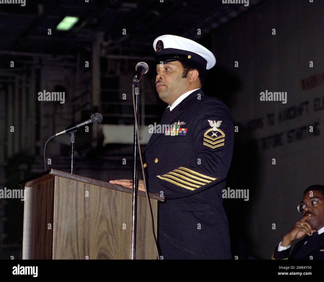 A chief petty officer addresses crew members and guests during a Black ...