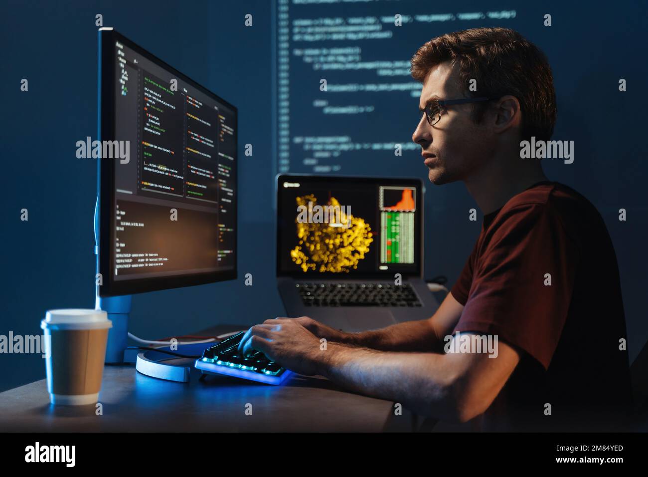 Profile view portrait of young guy data scientist working at pc at home late night, debugging ...