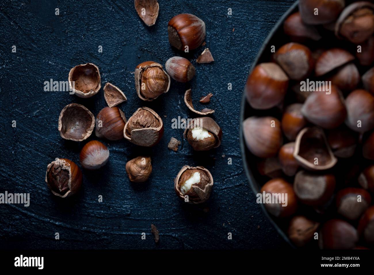 Cracked and unbroken shelled hazelnuts with a bowl of hazelnuts on a ...