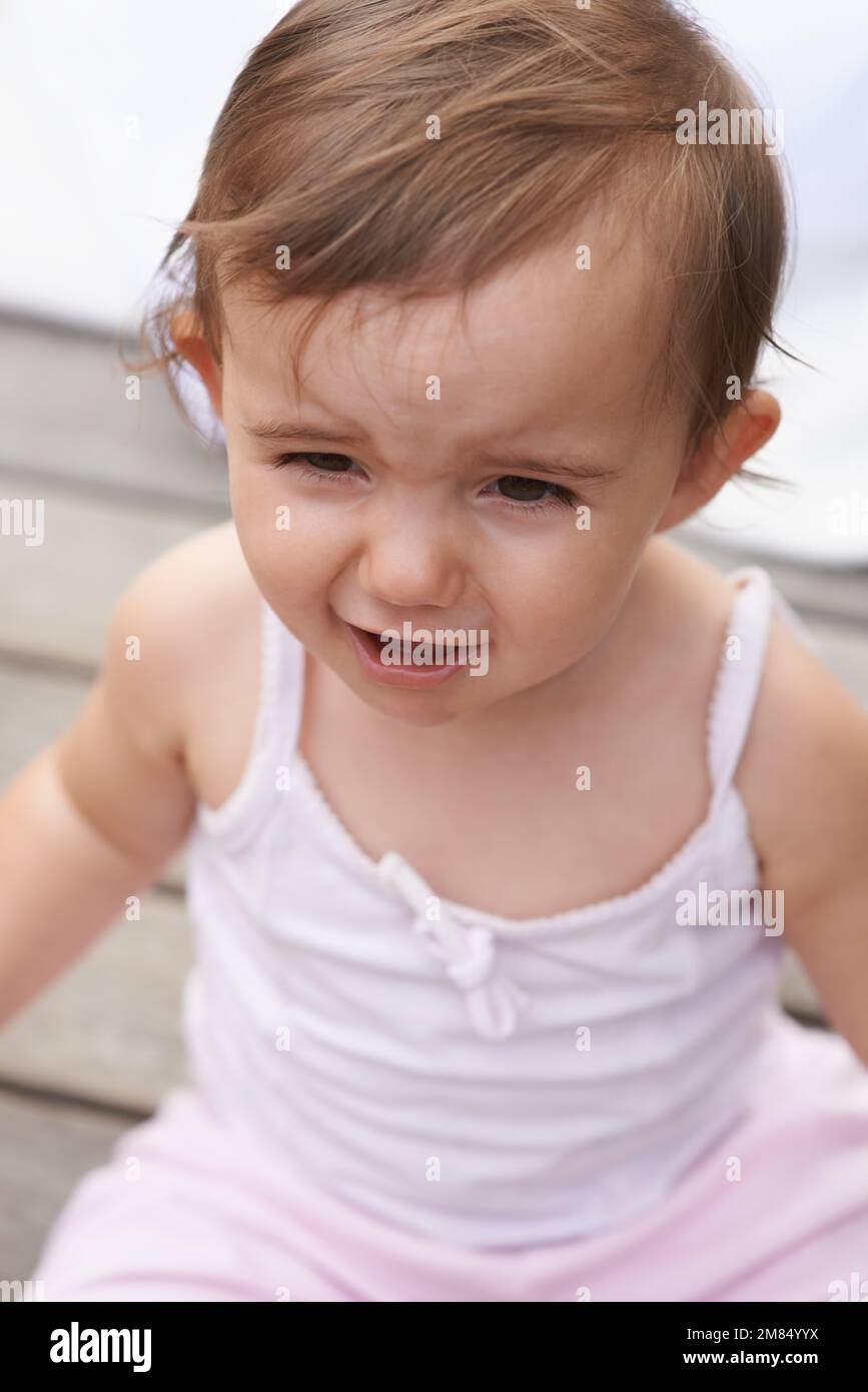 Shes not impressed...An unhappy little girl standing outside Stock ...