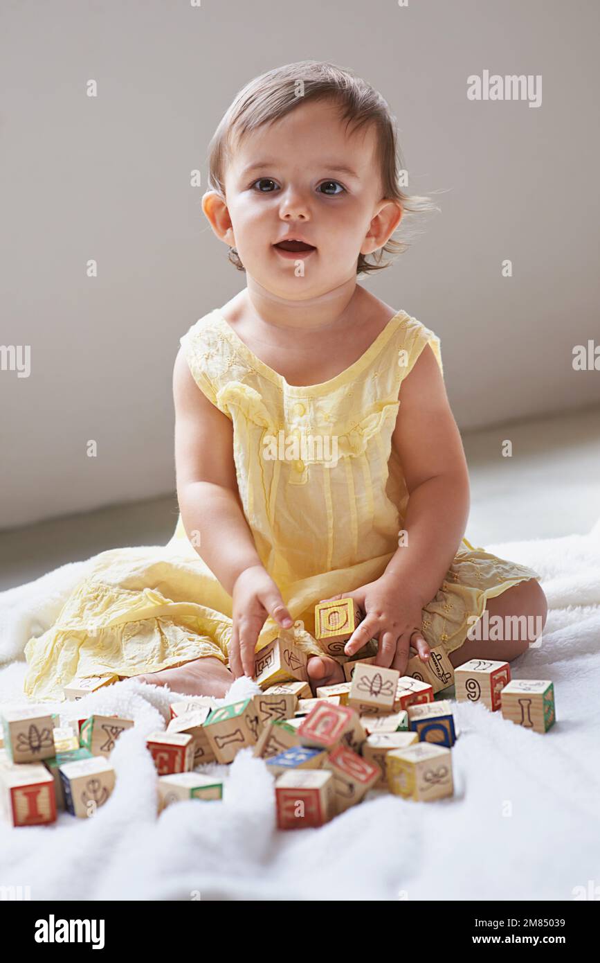 Shes so curious. a cute baby girl sitting on the floor playing with toy ...