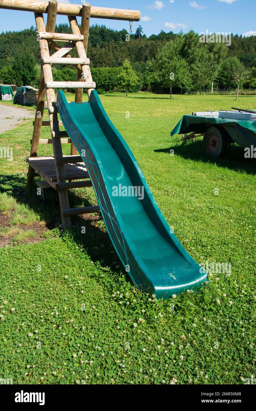 Plastic children's slide or kids slide with wooden stairs in the garden ...